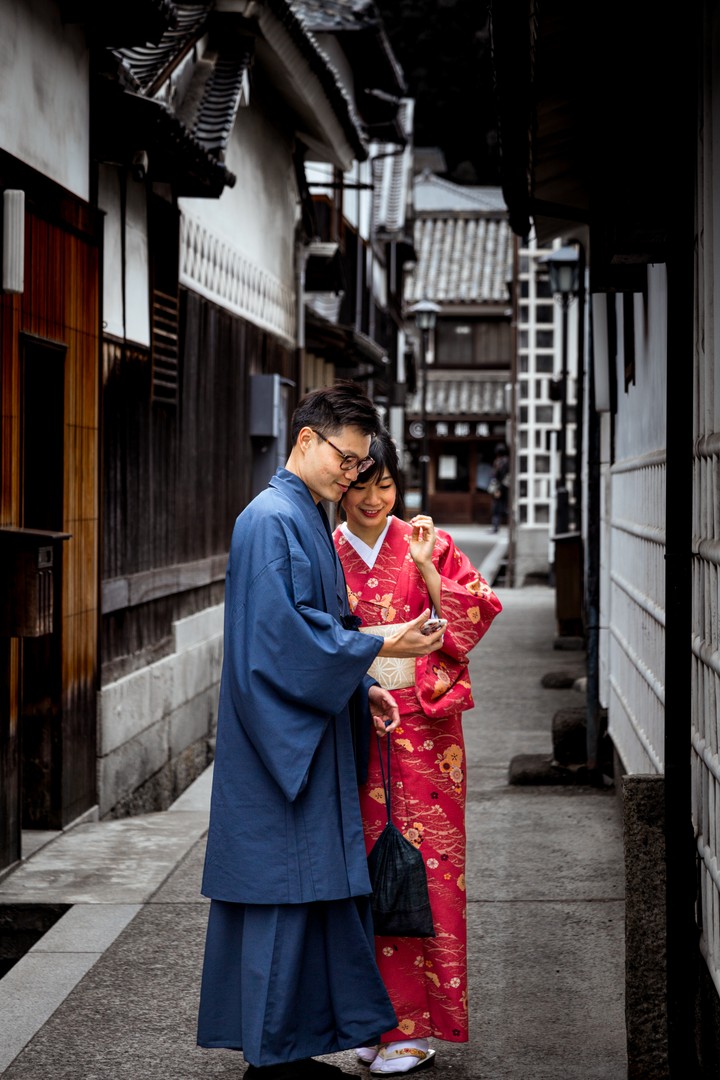 Smiling young couple wearing yukata and kimono in Edo period alleyway ...